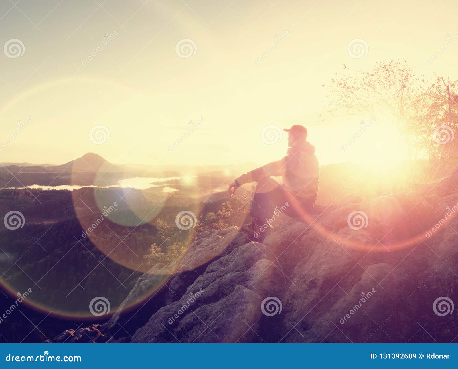 Man Alone on the Peak of Rock. Hiker Watching To Autumn Sun at Horizon ... Man Alone on the Peak of Rock. Hiker Watching To Autumn Sun at Horizon ...