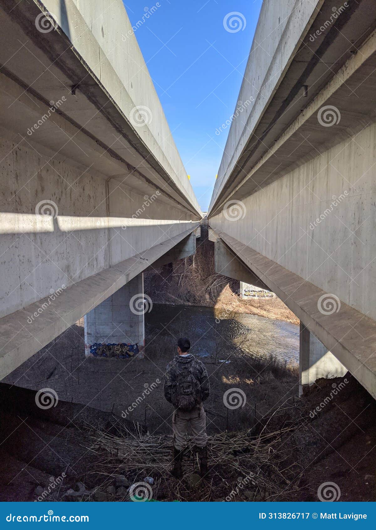 A Man Stands Under a Bridge Over a Valley with a River Stock Image ...