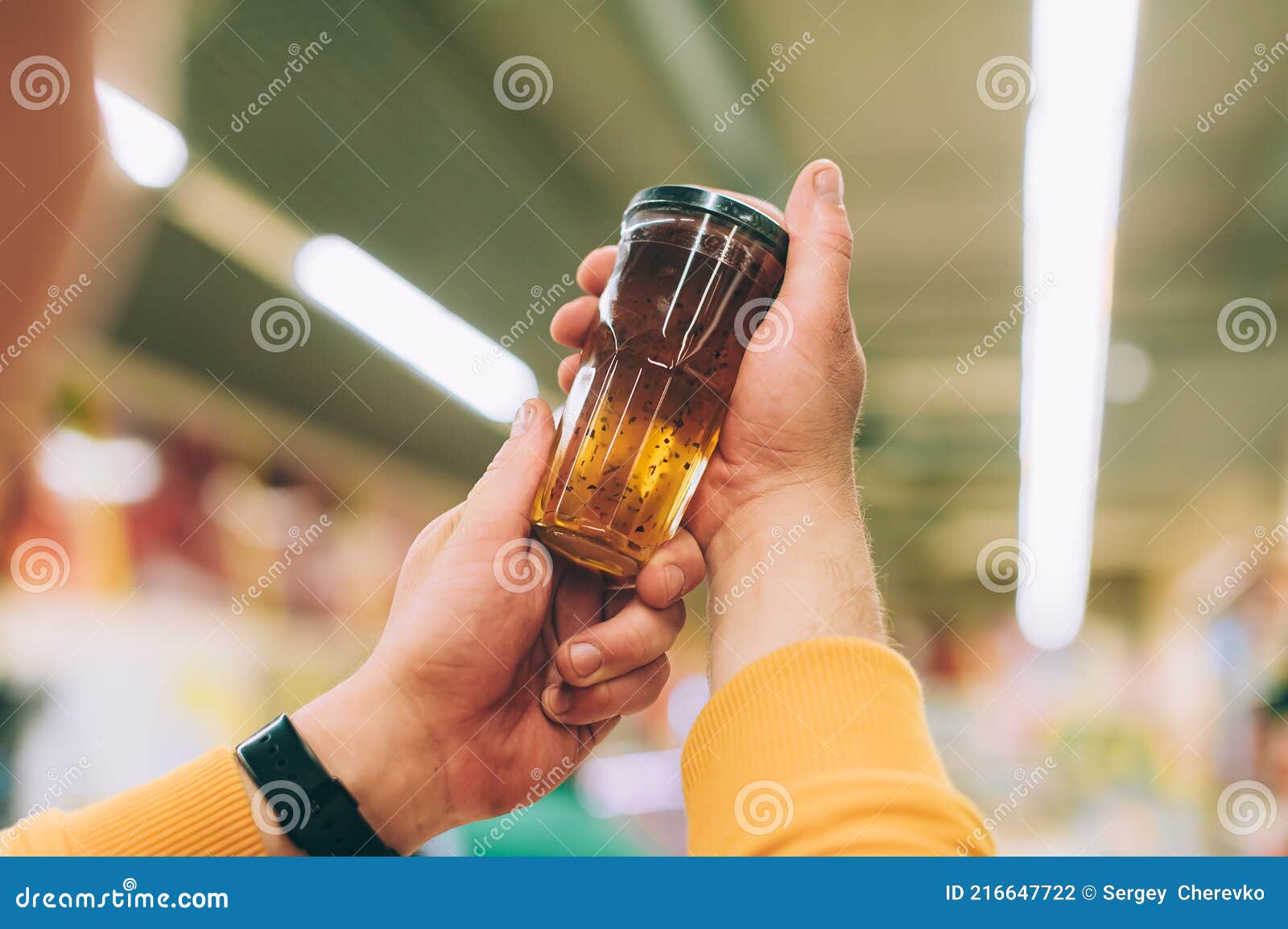 Man in a Store Holds a Jar of Jam in His Hand, Against the Backdrop of ...