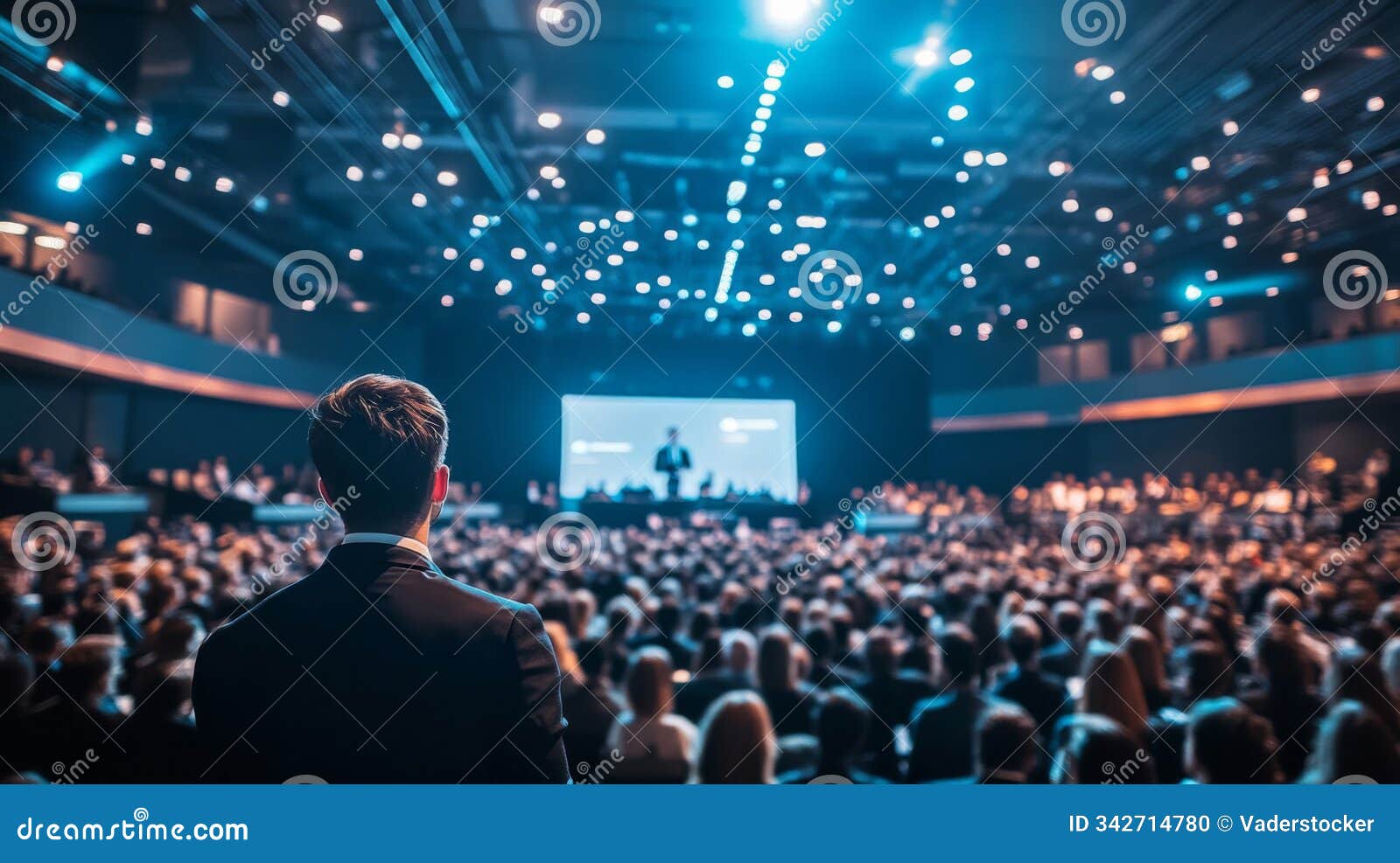 A Man in a Suit Facing a Large Audience in a Convention Hall Stock ...