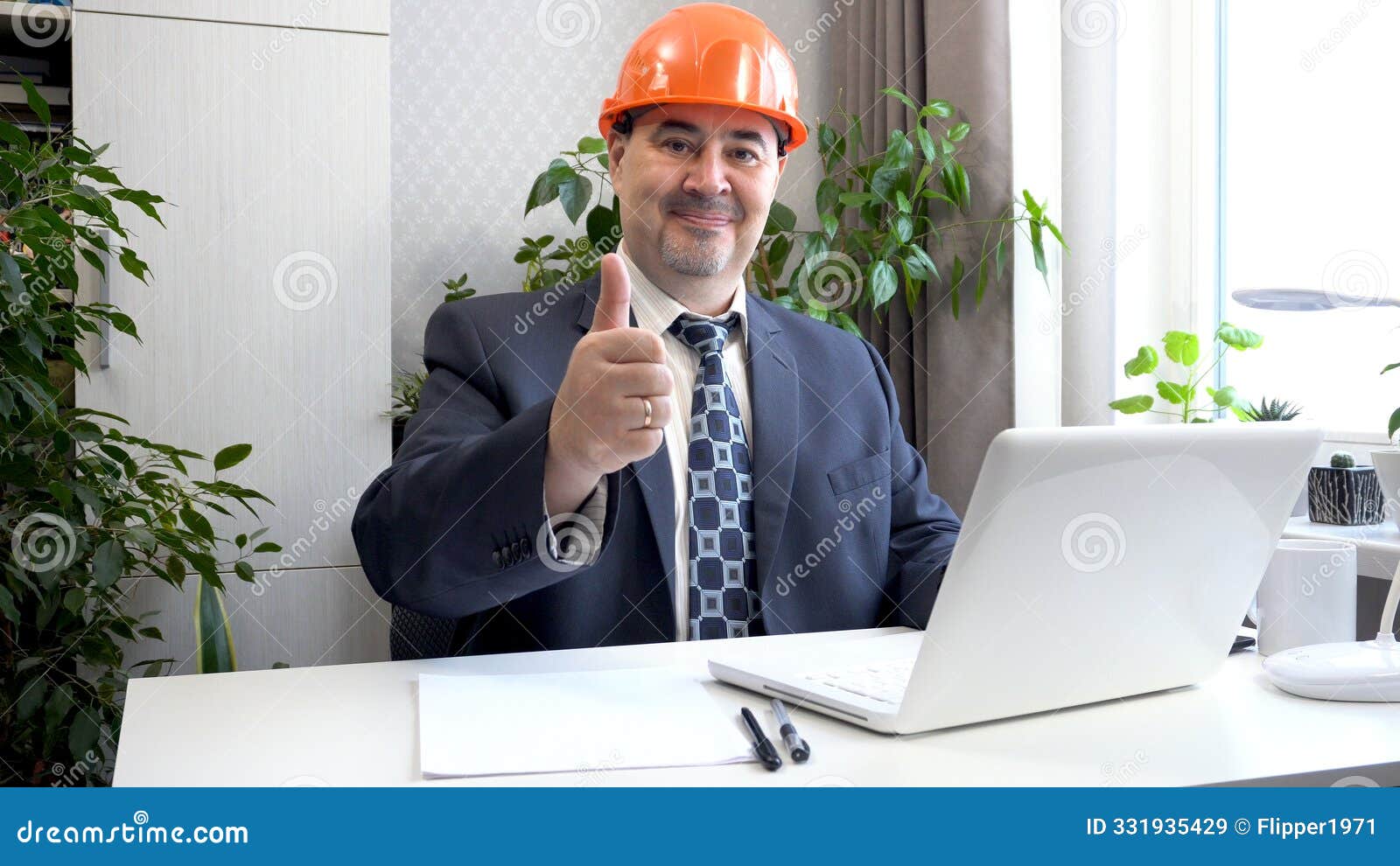 A Man in a Suit and Hard Hat at a Computer. he is Looking at the Camera ...