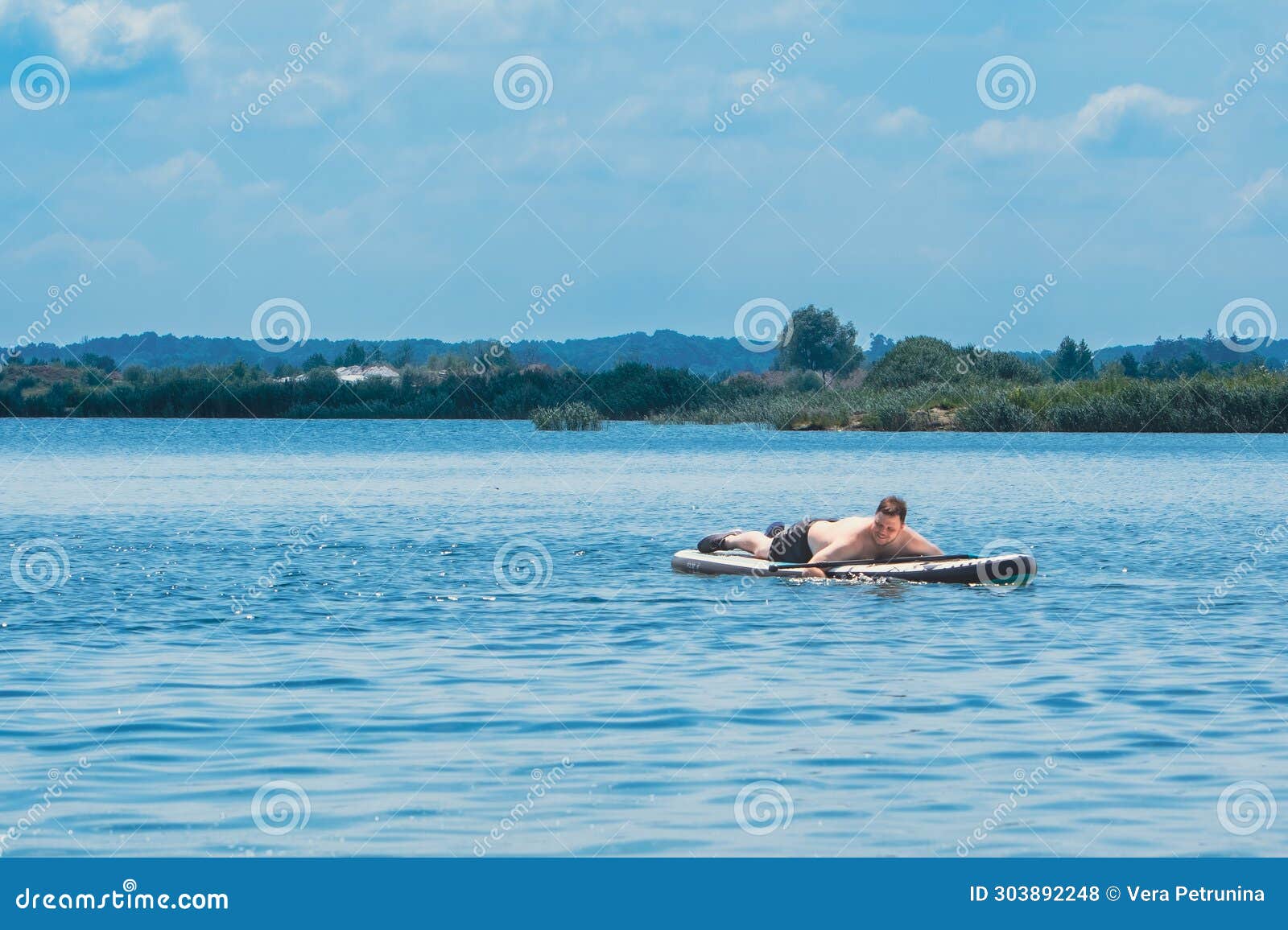 Man Sunbathing on Supboard in the Middle of the Lake Stock Photo ...