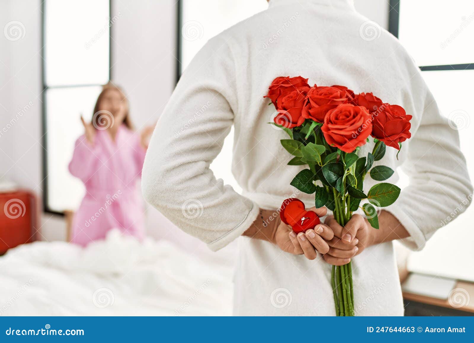 Man Surprising His Girlfriend With Bouquet Of Roses At Bedroom Stock