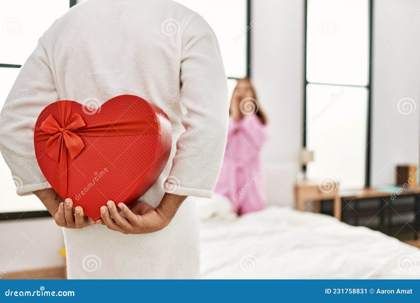 Man Surprising His Girlfriend With Valentine Heart Box T At Bedroom