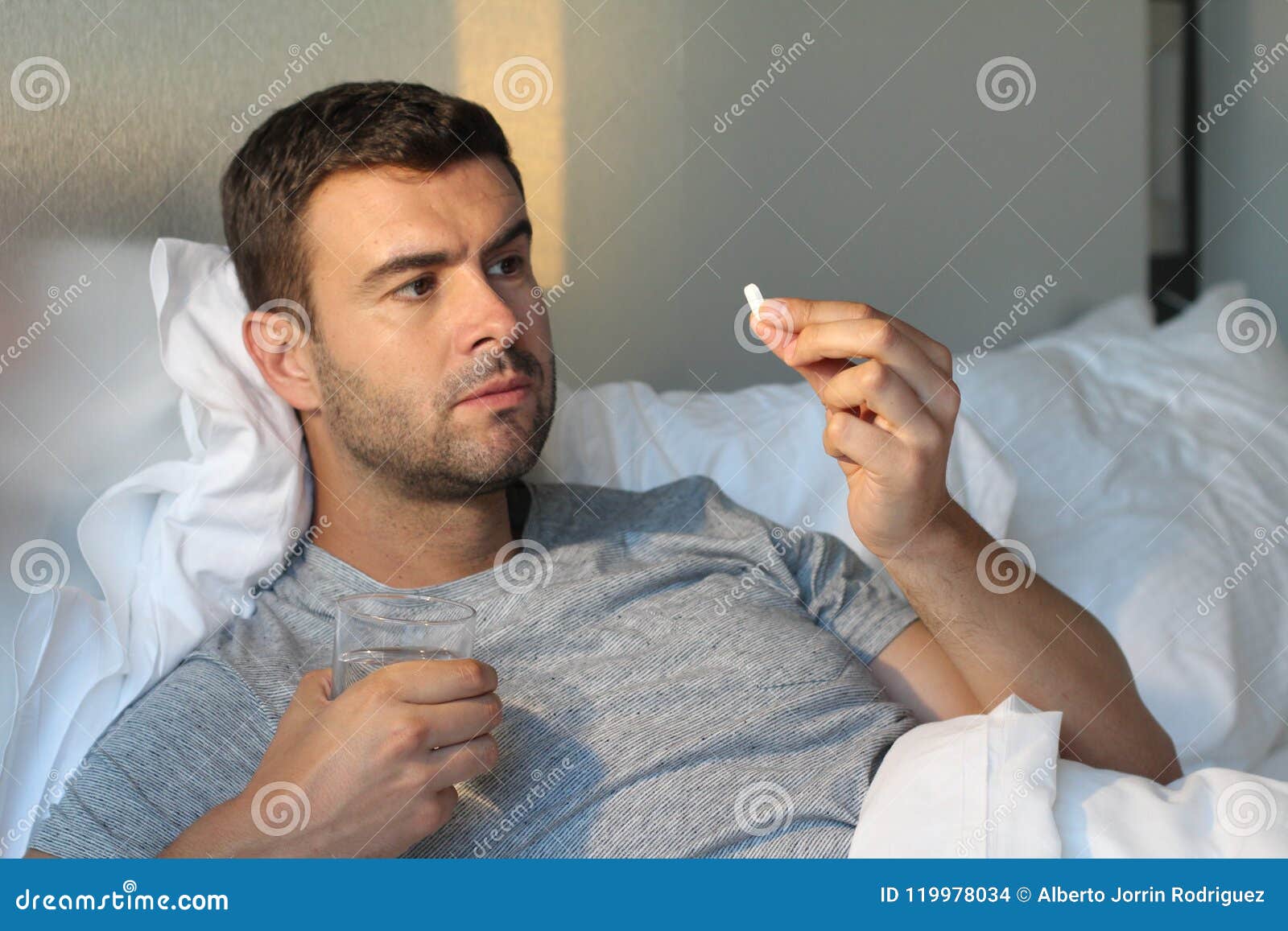 Man taking a pill in bed stock photo. Image of leaning - 119978034