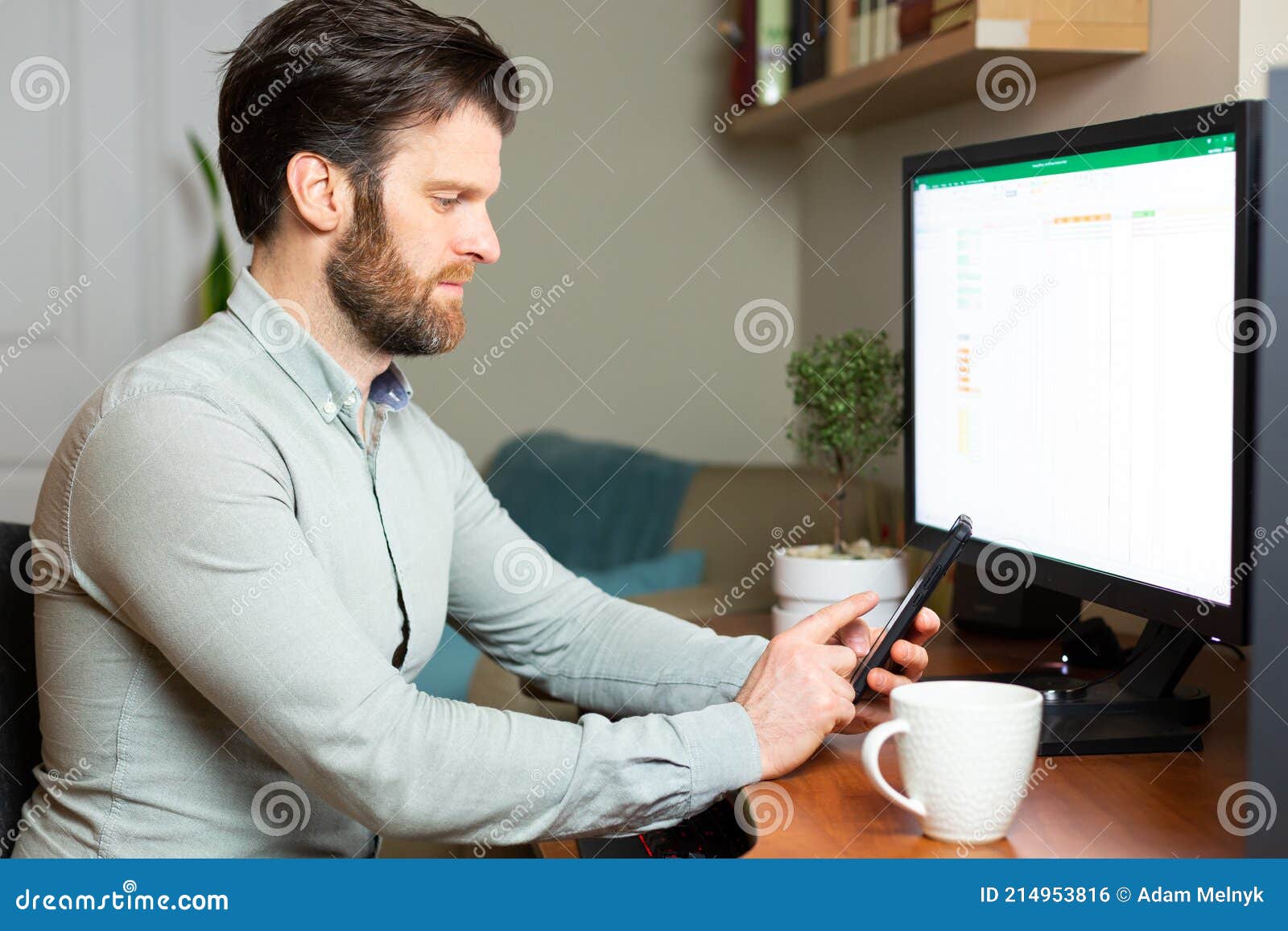 Man Taking Video Call on His Cell Phone Working from Home on Desktop ...