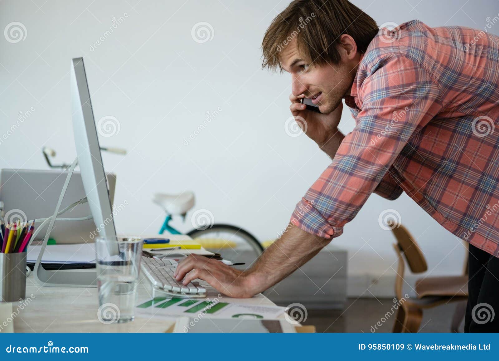 Man Talking on Phone while Using Computer at Desk Stock Image - Image ...