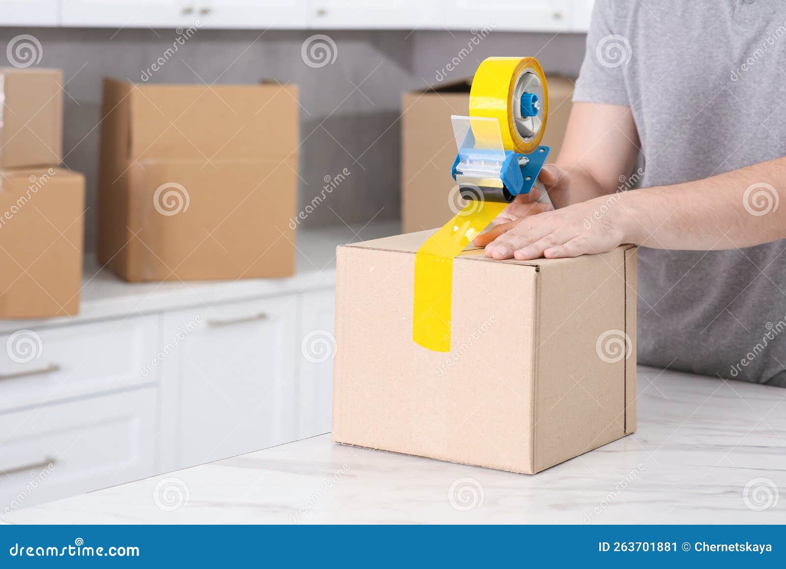 Man Taping Box with Adhesive Tape Dispenser in Kitchen, Closeup Stock ...
