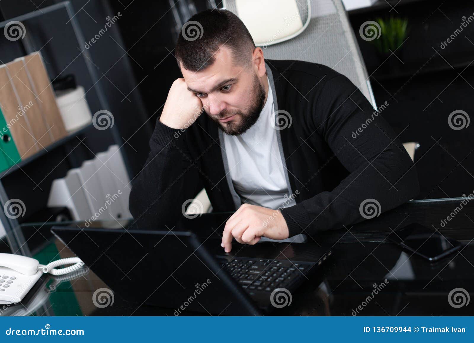 Portrait of Young Man Propping Up His Head with His Fist with Laptop in ...