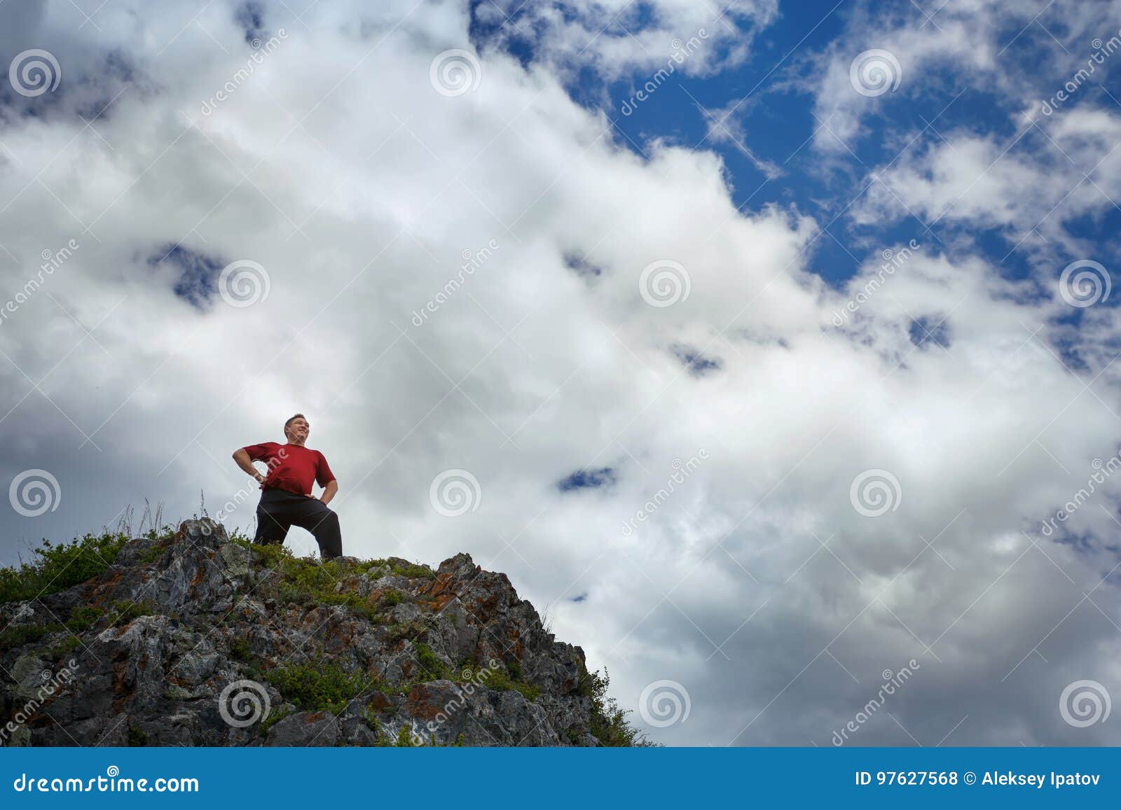A Man on Top of a Mountain Against a Blue Sky with Clouds. Stock Photo ...