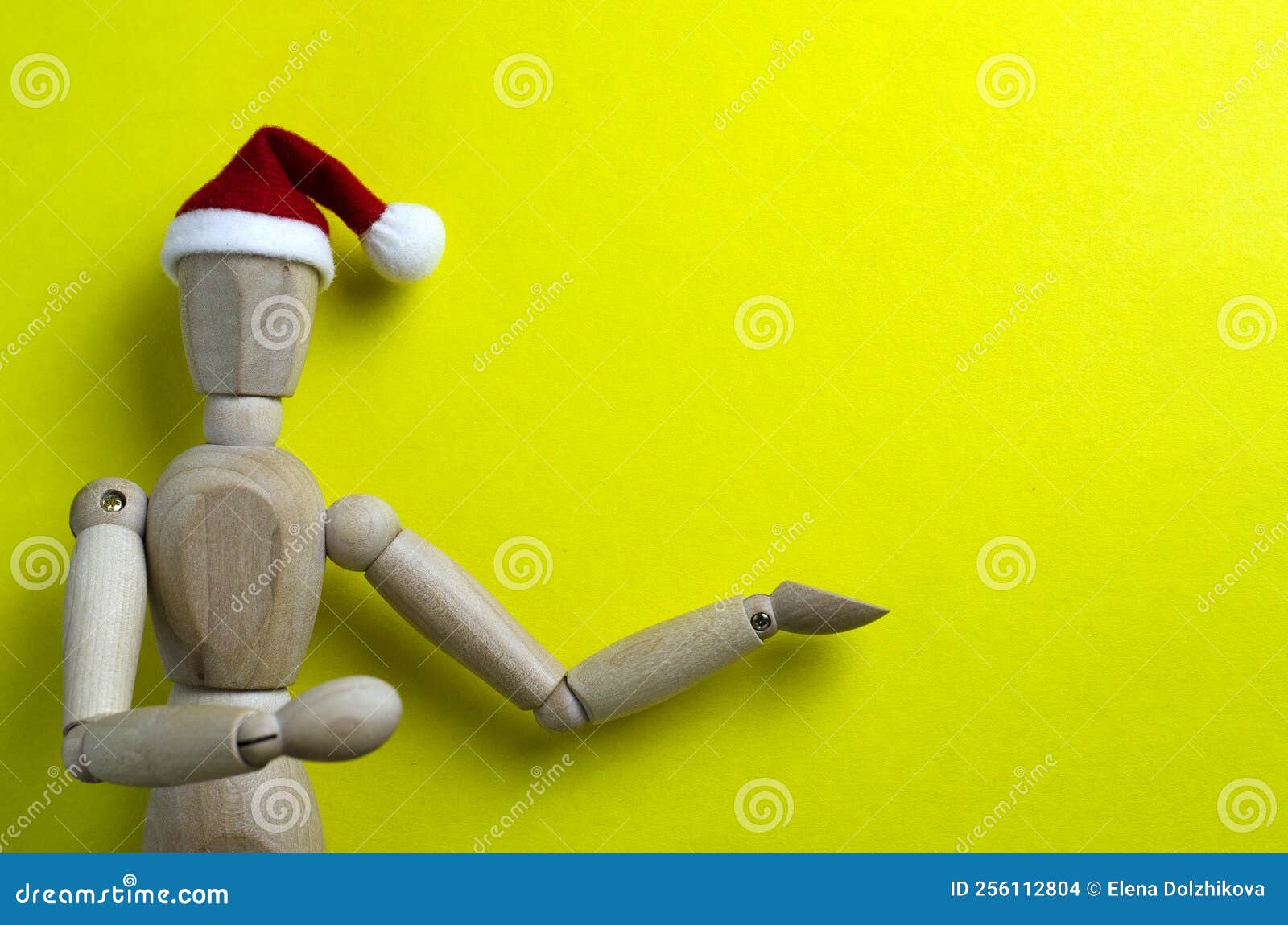 A Man Toy in a Santa Hat on a Yellow Background Points To an Empty ...