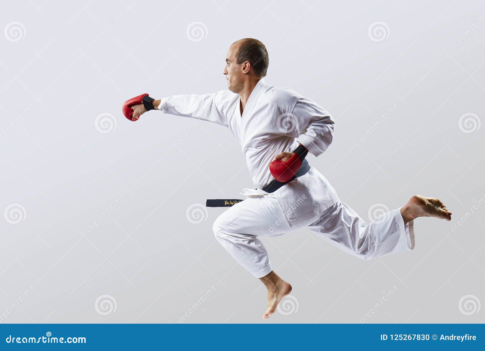 A Man is Training a Punch with a Hand in a Jump Against a Light ...