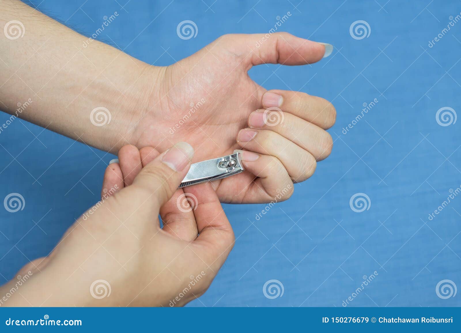 A Man Trims His Fingernails Using a Metallic Pair of Nail Clippers ...