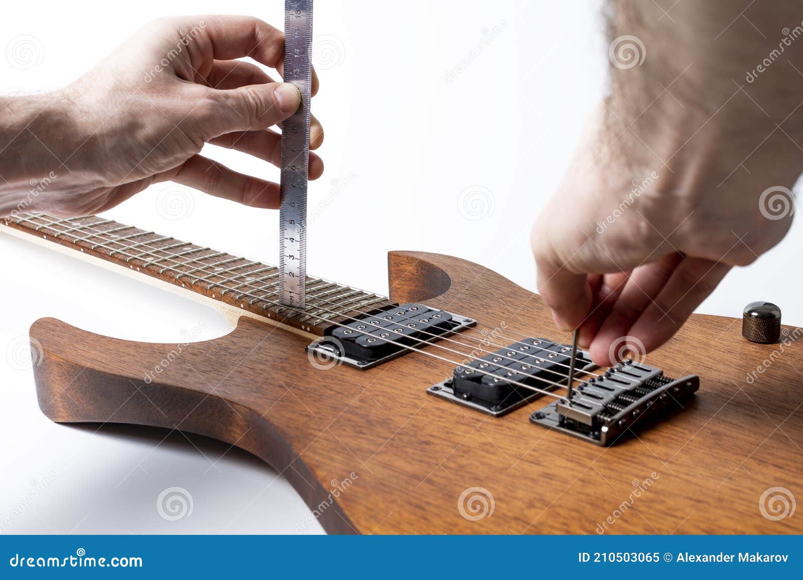 A Man is Tuning and Adjusting a New Electric Guitar Using Measuring ...