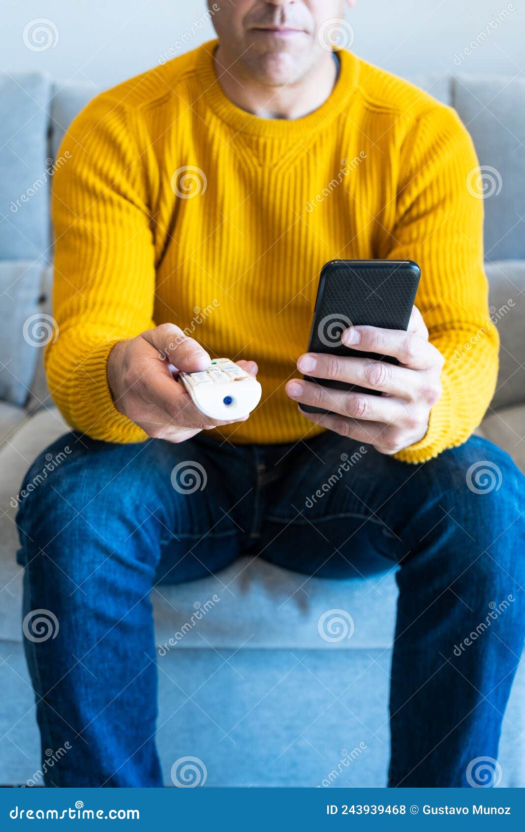 Man with TV Remote Control and Smartphone in His Hands on the Sofa ...