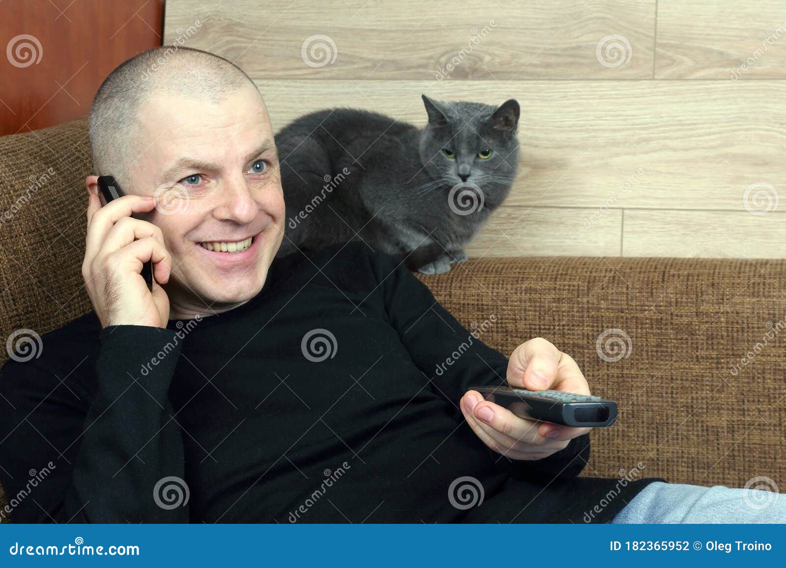 The Man with the TV Remote in Hand Talking on the Phone and Watching TV ...