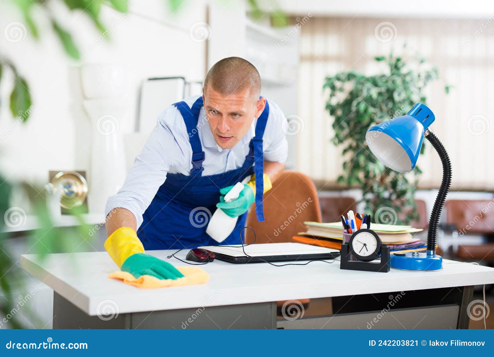 Man in Uniform is Cleaning Dust from the Desk in Office Stock Image ...