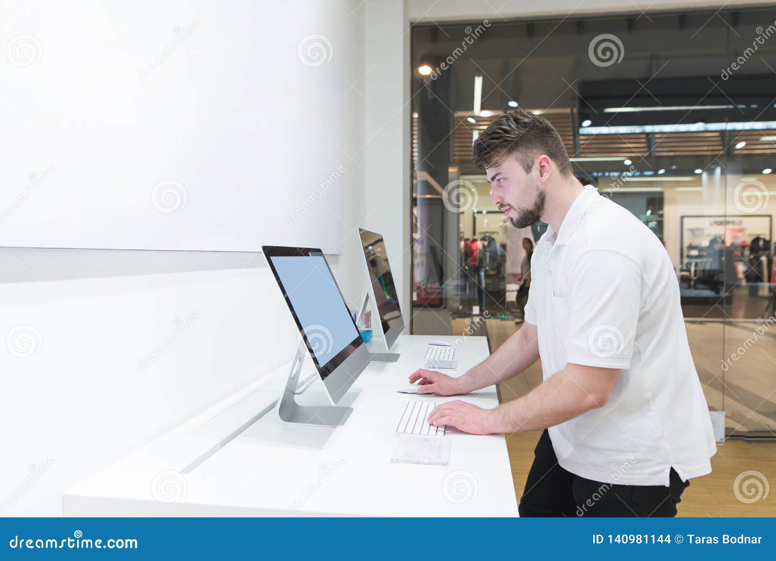 Man Uses a Computer in a Modern Electronics Store. Buyer Selects a ...
