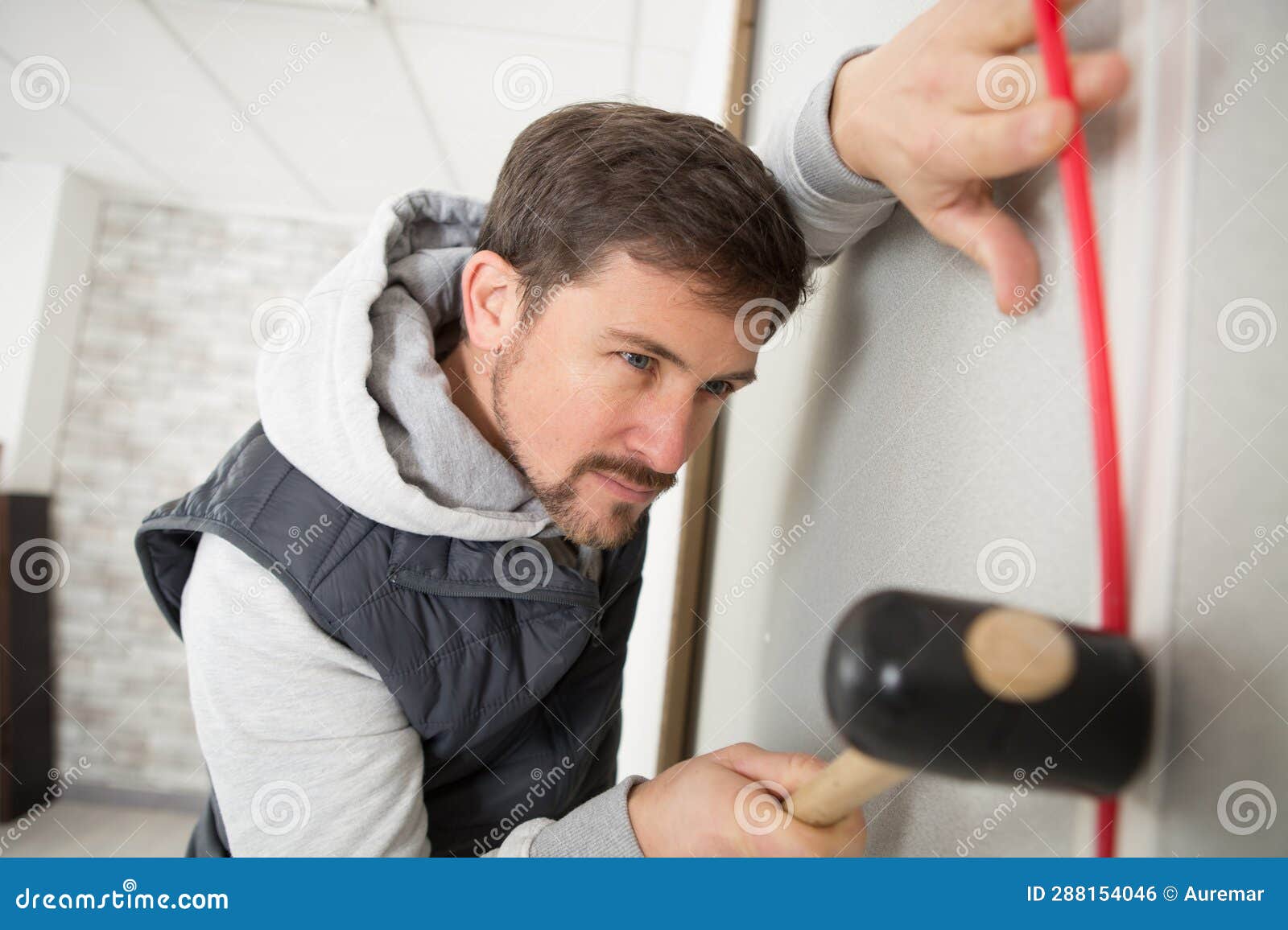 Man uses hammer on wall stock photo. Image of installing - 288154046