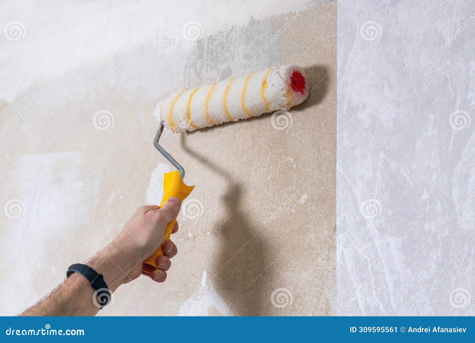 A Man Uses a Roller To Apply Glue To a Wall To Paste Wallpaper. Room ...