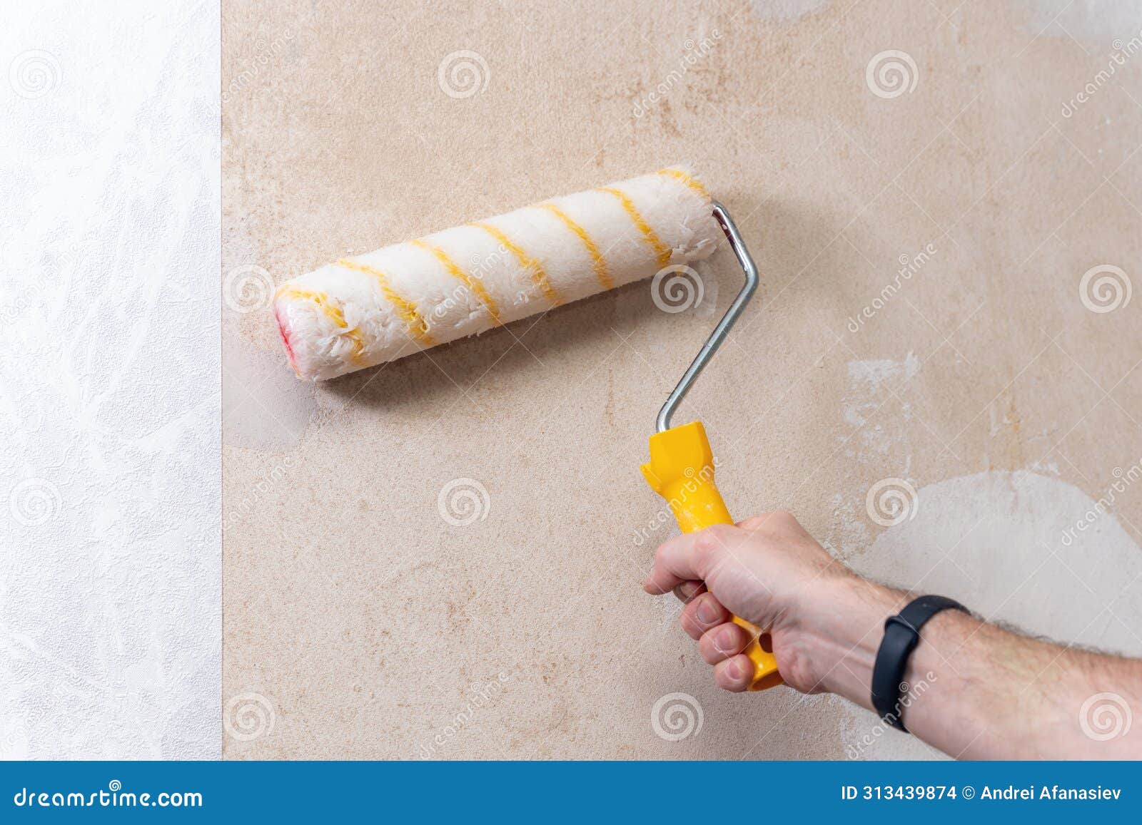 A Man Uses a Roller To Apply Glue To a Wall To Paste Wallpaper. Room ...