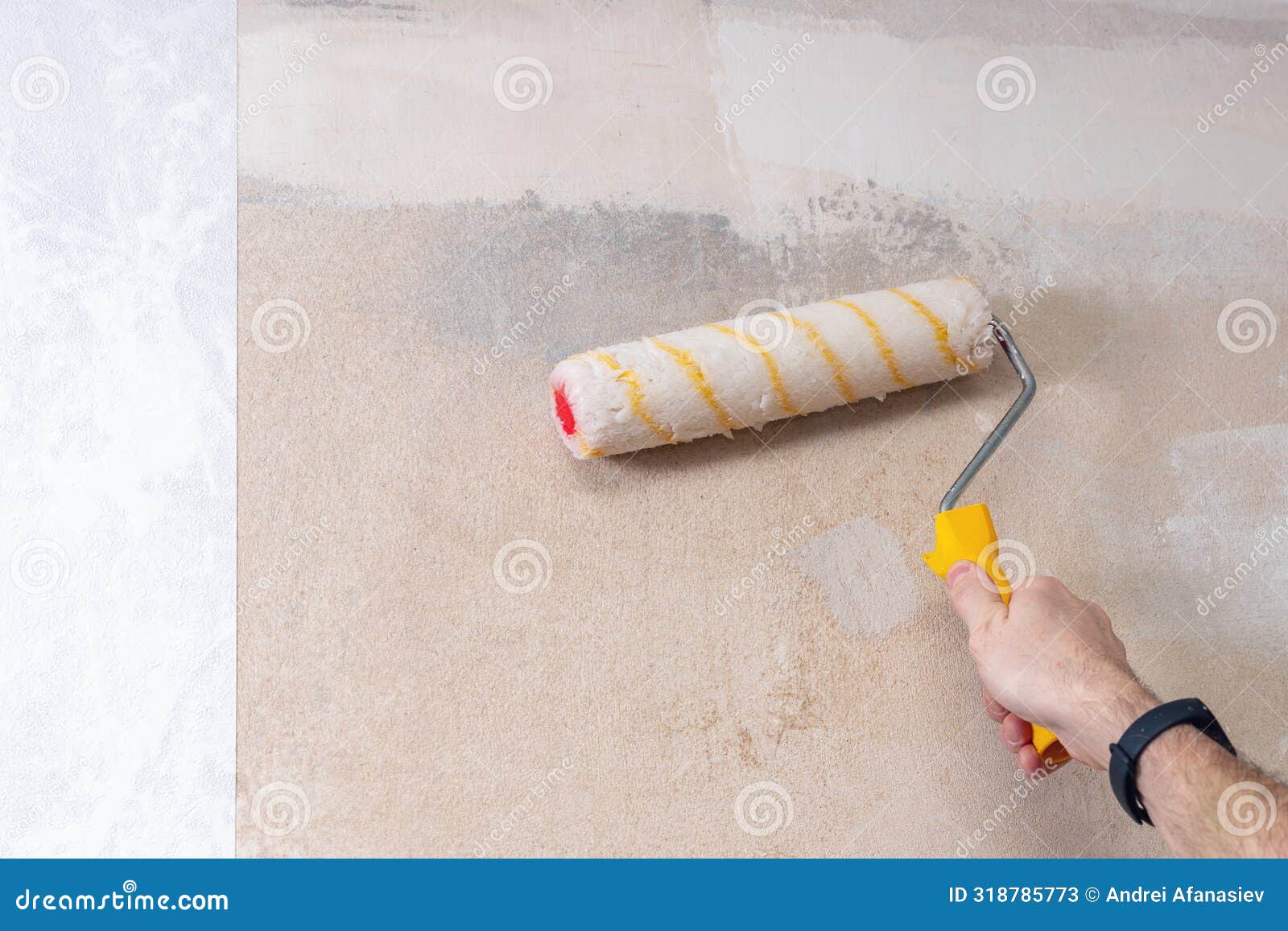 A Man Uses a Roller To Apply Glue To a Wall To Paste Wallpaper. Room ...