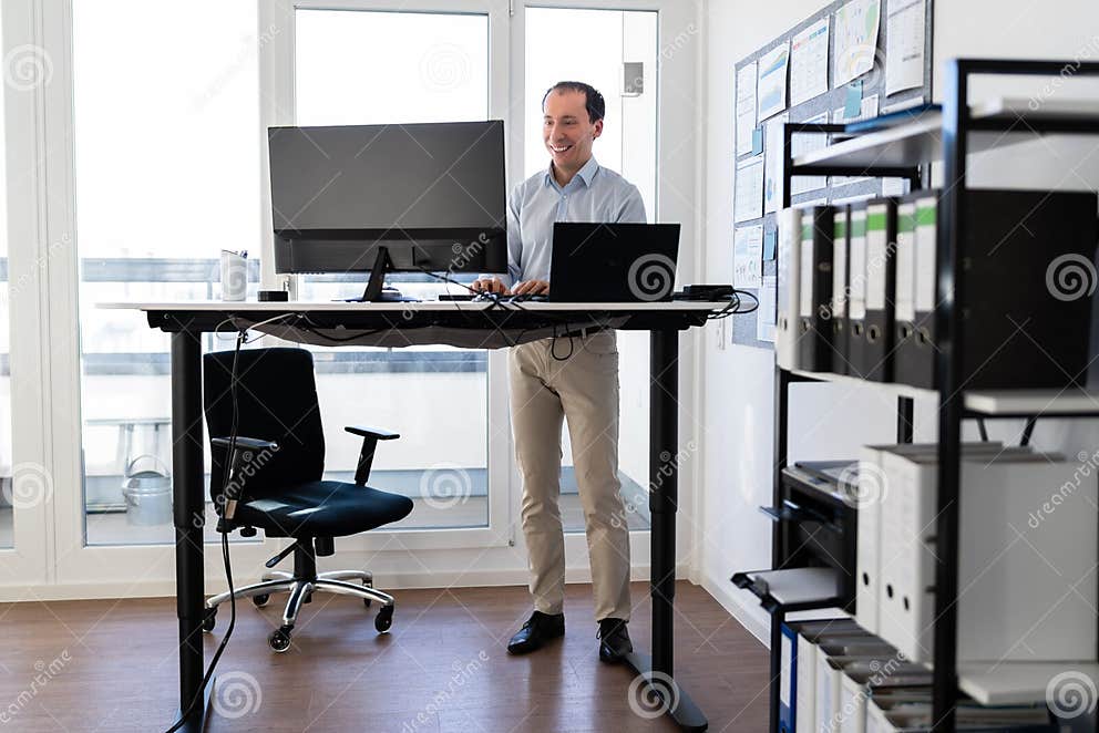 Man Using Adjustable Height Standing Desk in Office Stock Image - Image ...