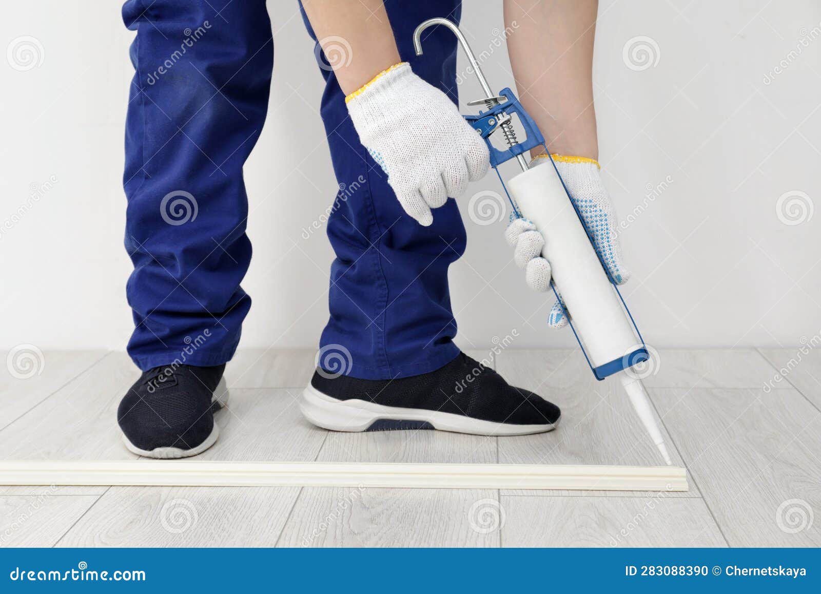 Man Using Caulking Gun while Installing Plinth on Laminated Floor in ...
