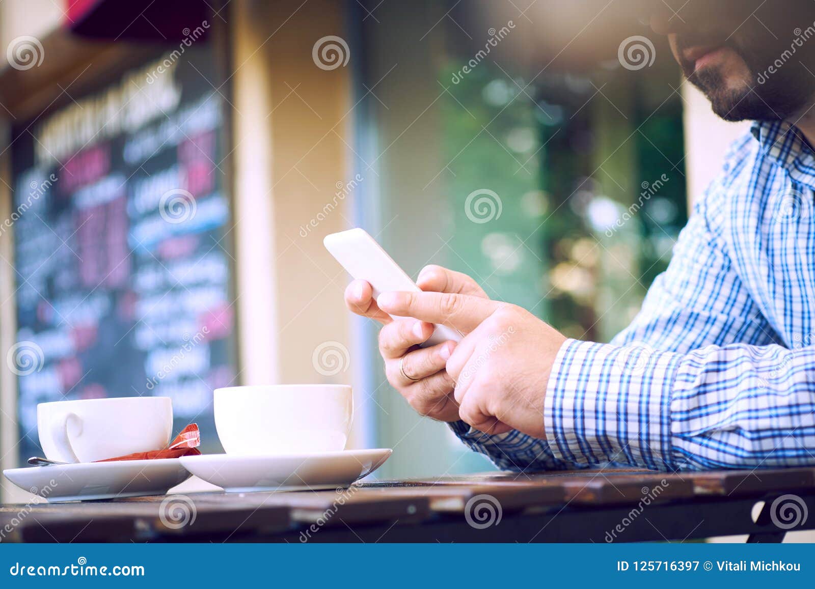 Man Using a Cell Phone on Cafe Terrace and Drinking Coffee. Man Drinks ...