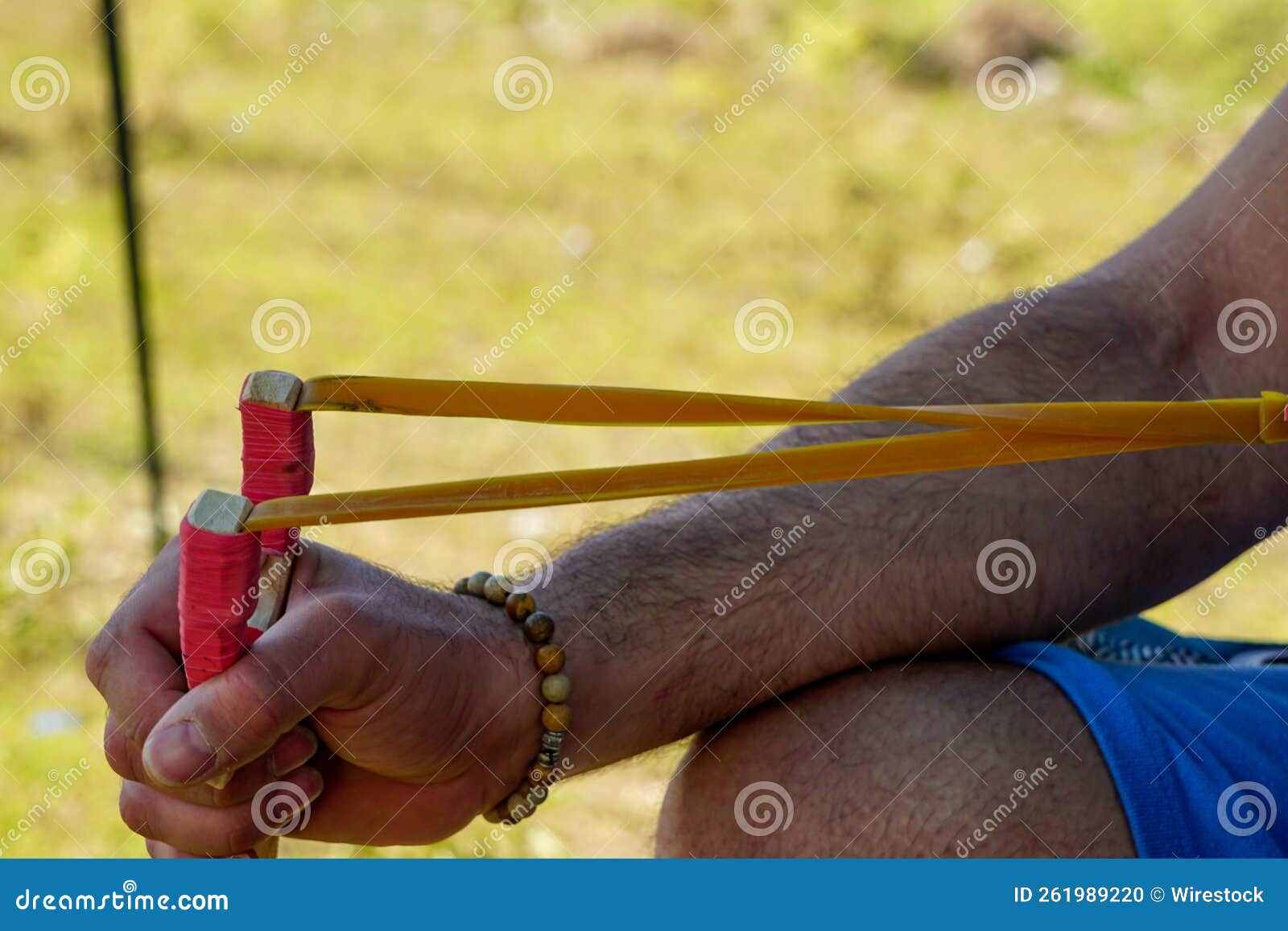 Man Using a Handmade Rubber Slingshot Against a Blurred Background ...
