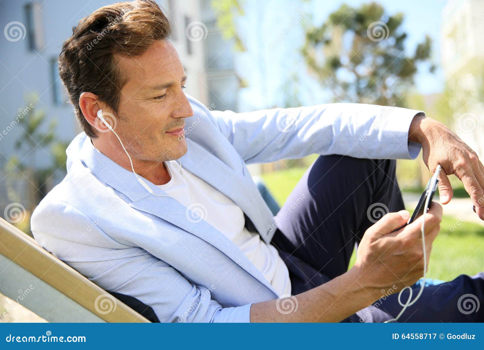 Man Using Headphones Talking on Smartohone in Public Park Stock Image ...