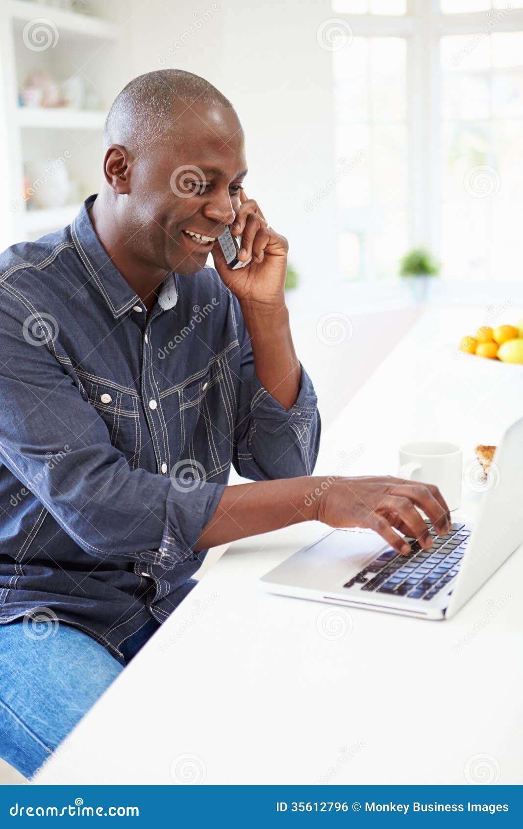 Man Using Laptop and Talking on Phone in Kitchen at Home Stock Photo ...