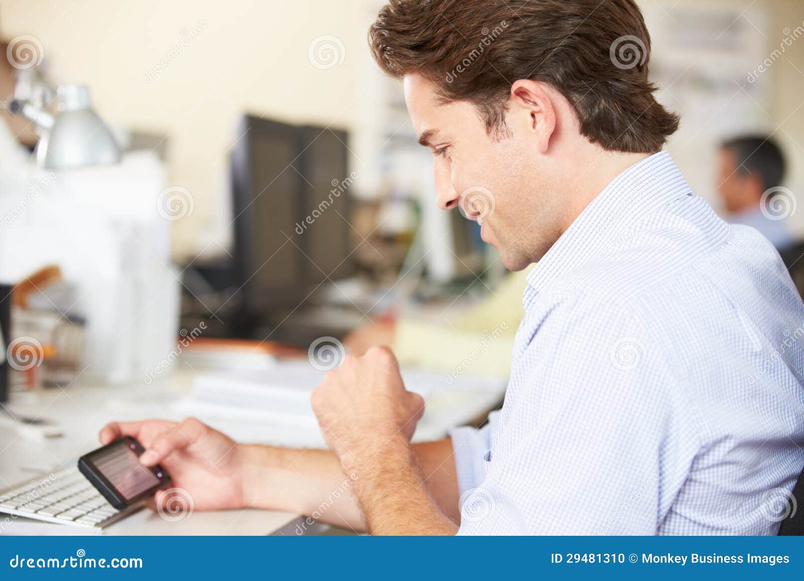 Man Using Mobile Phone at Desk in Busy Creative Office Stock Photo ...