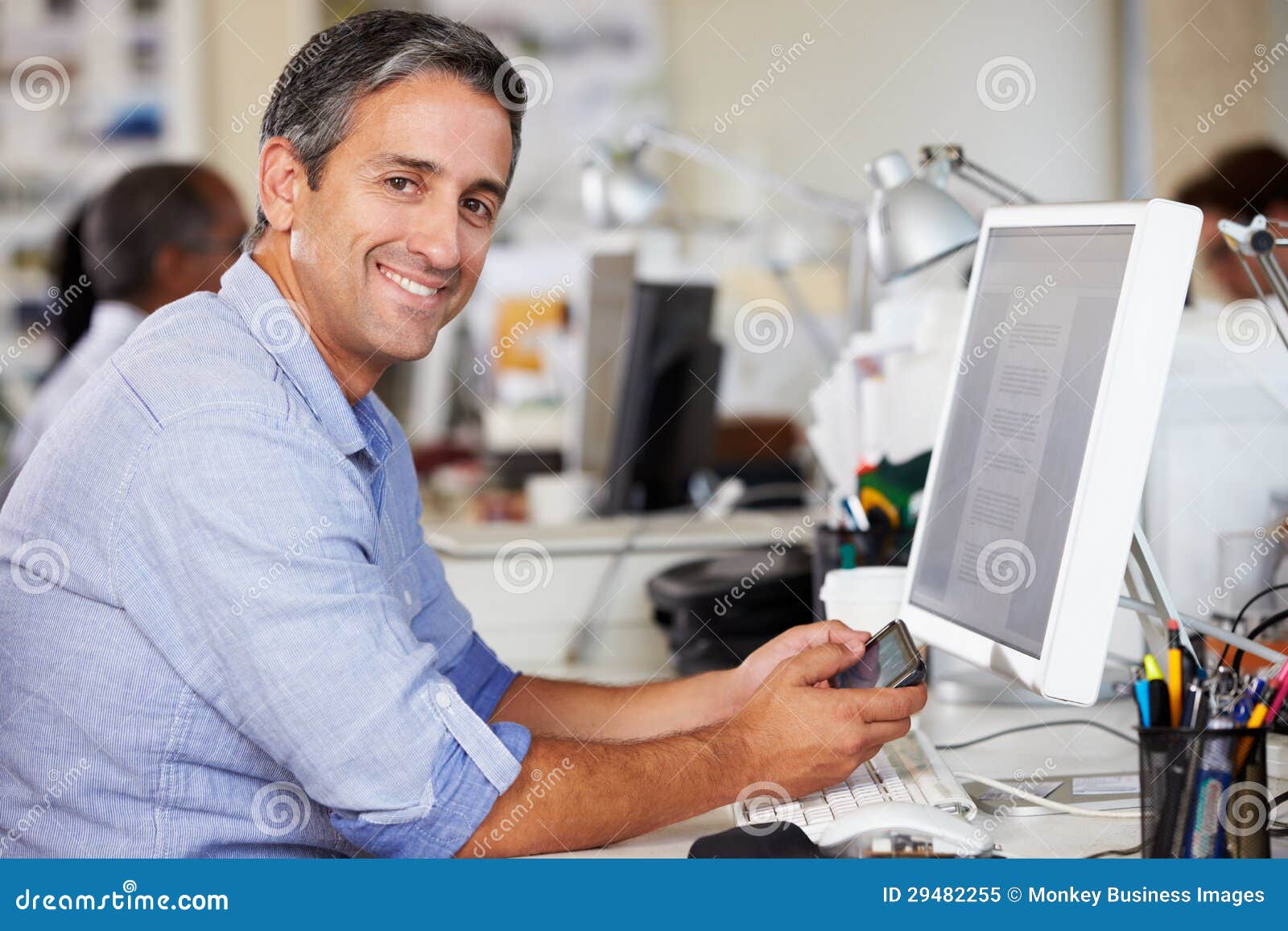 Man Using Mobile Phone at Desk in Busy Creative Office Stock Image ...