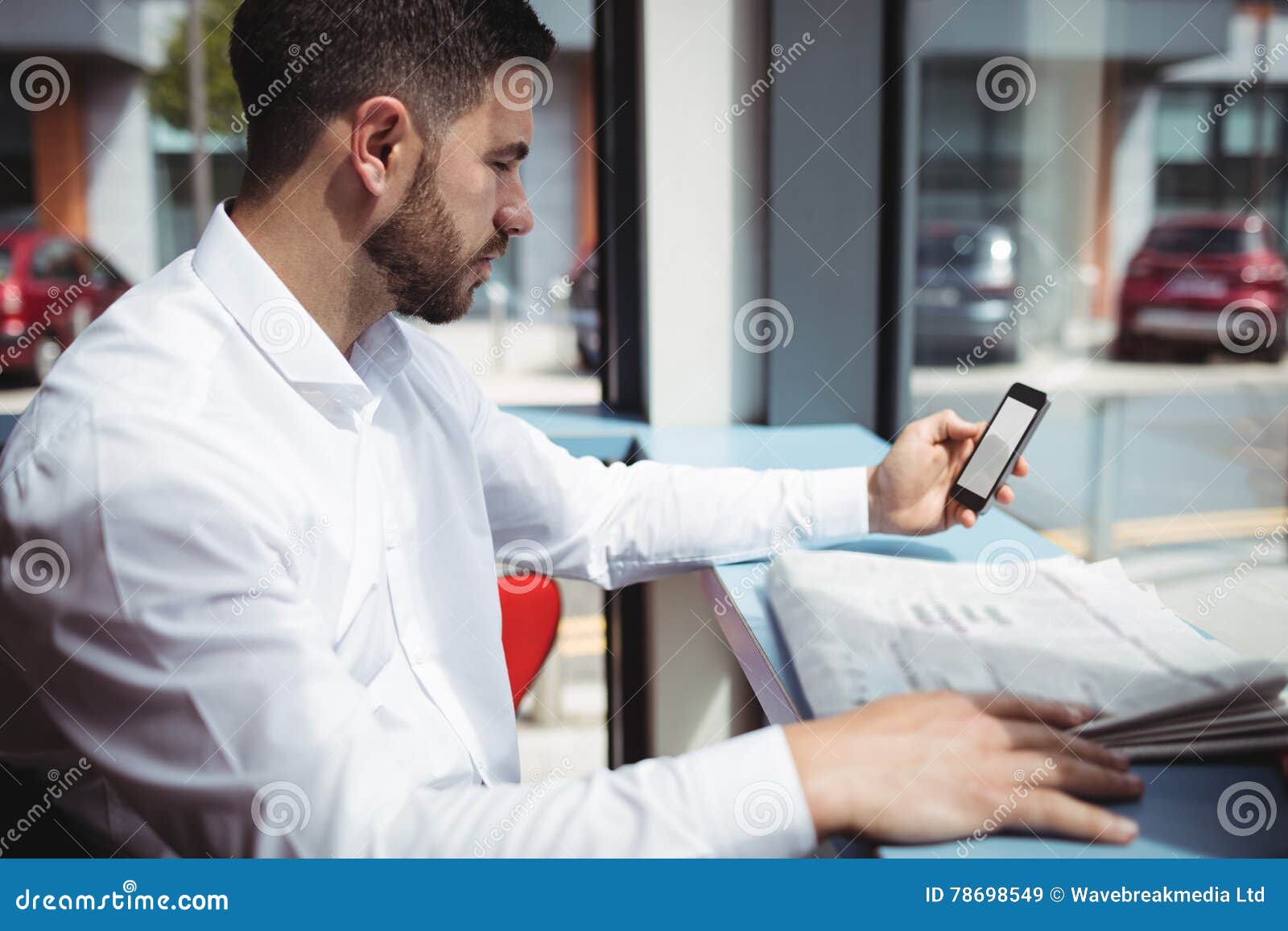 Man Using Mobile Phone while Reading Newspaper Stock Image - Image of ...