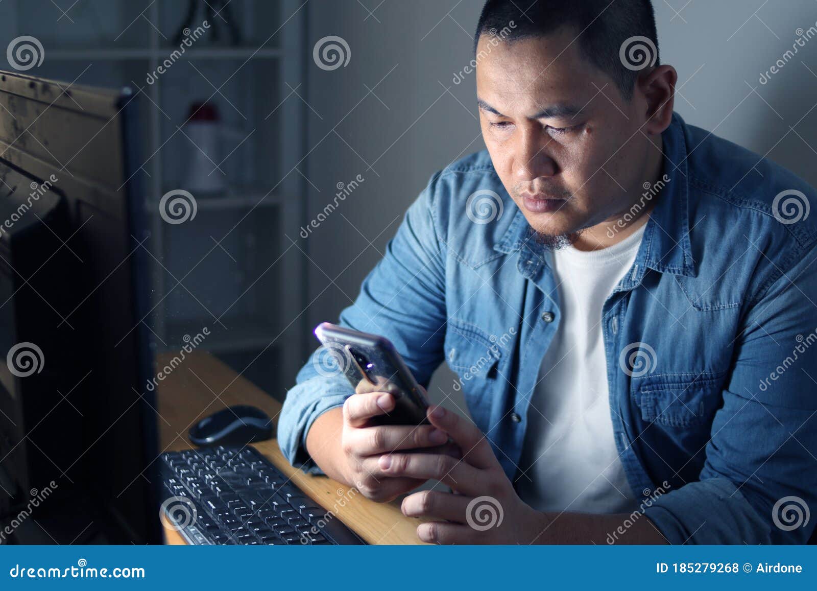 Man Using Phone Application and Working on His Computer at Night ...