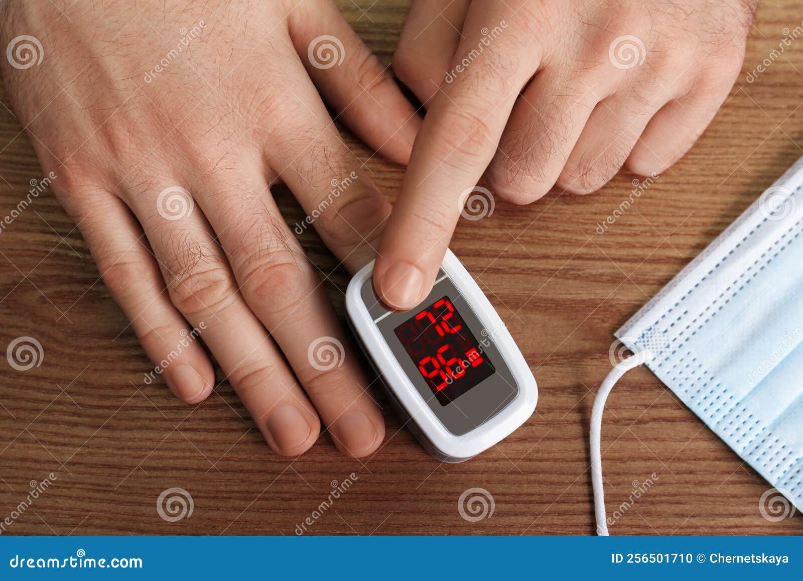 Man Using Pulse Oximeter for Oxygen Level Testing at Wooden Table with ...