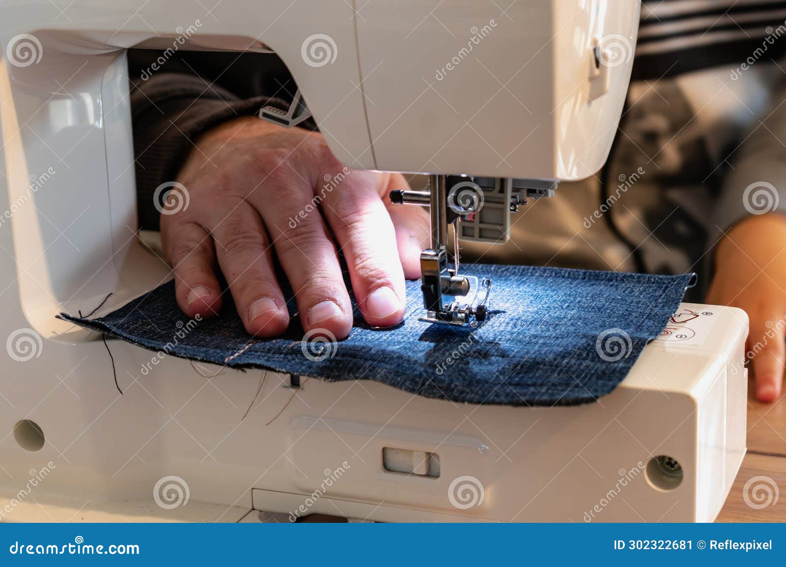 Man Using a Sewing Machine with a Blue Garment, for Repair Work ...