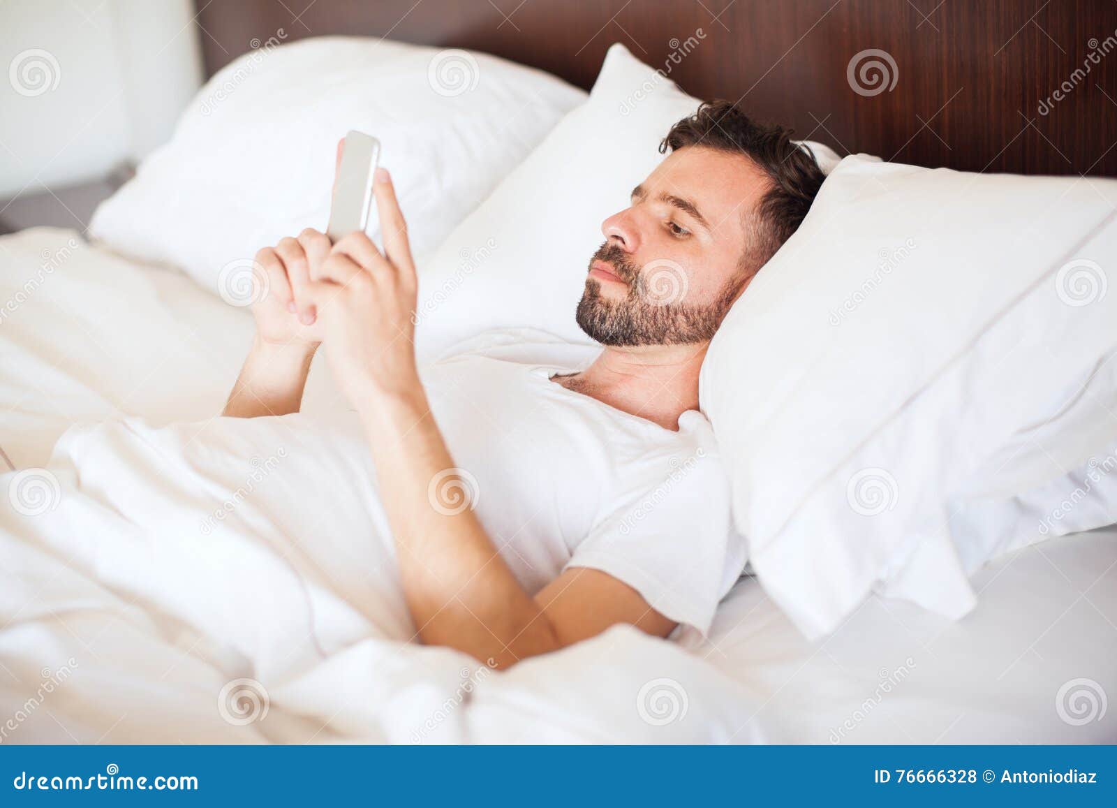 Man Using a Smartphone on His Bed Stock Photo - Image of lying, male ...