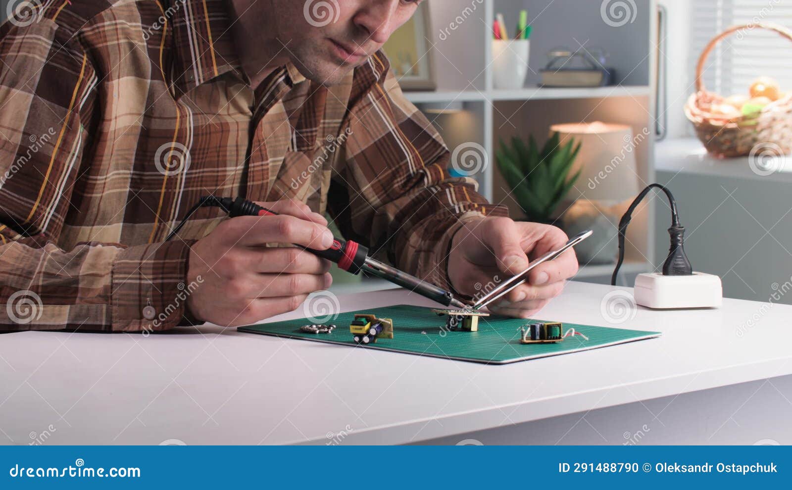 Man Using Soldering Iron Repairs Electrical Microcircuits on a Table at ...