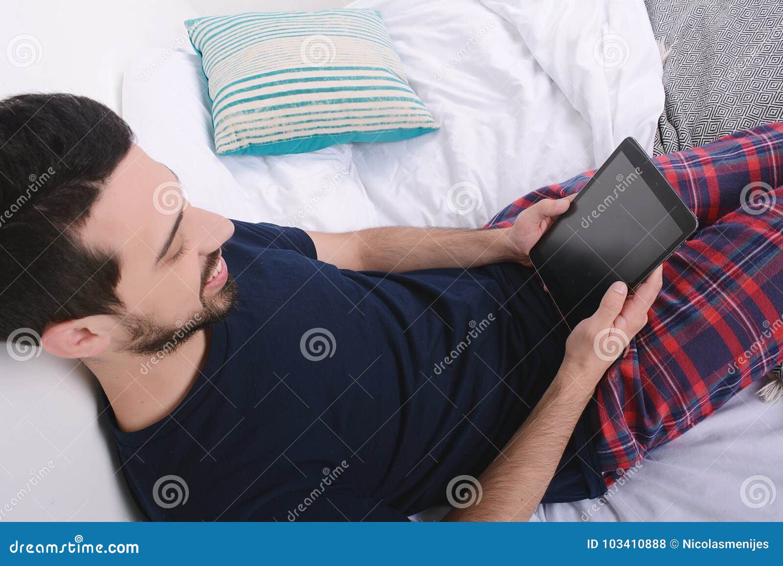 Man using tablet on bed. stock photo. Image of laying - 103410888