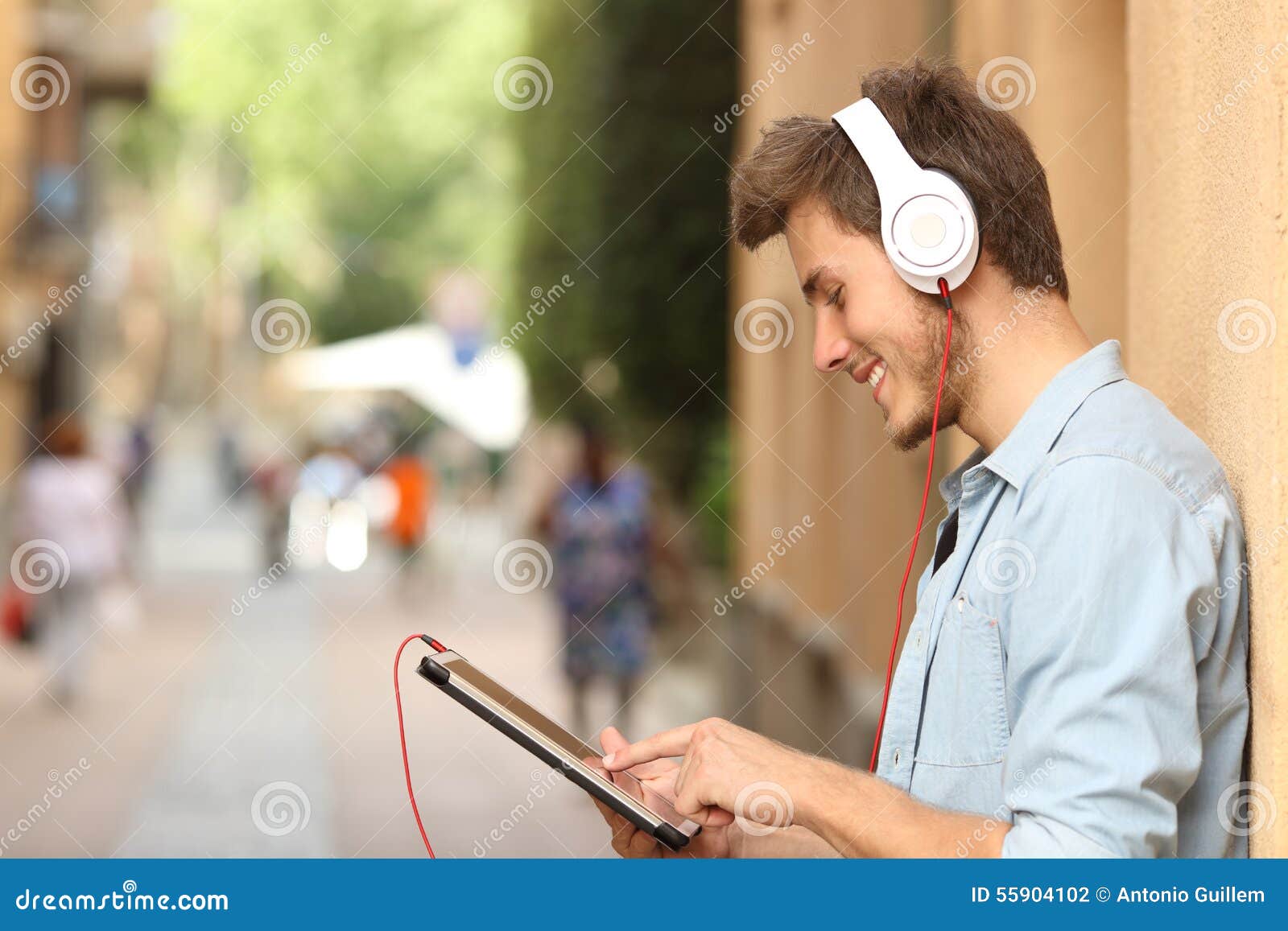 Man Using a Tablet with Headphones on the Street Stock Photo - Image of ...
