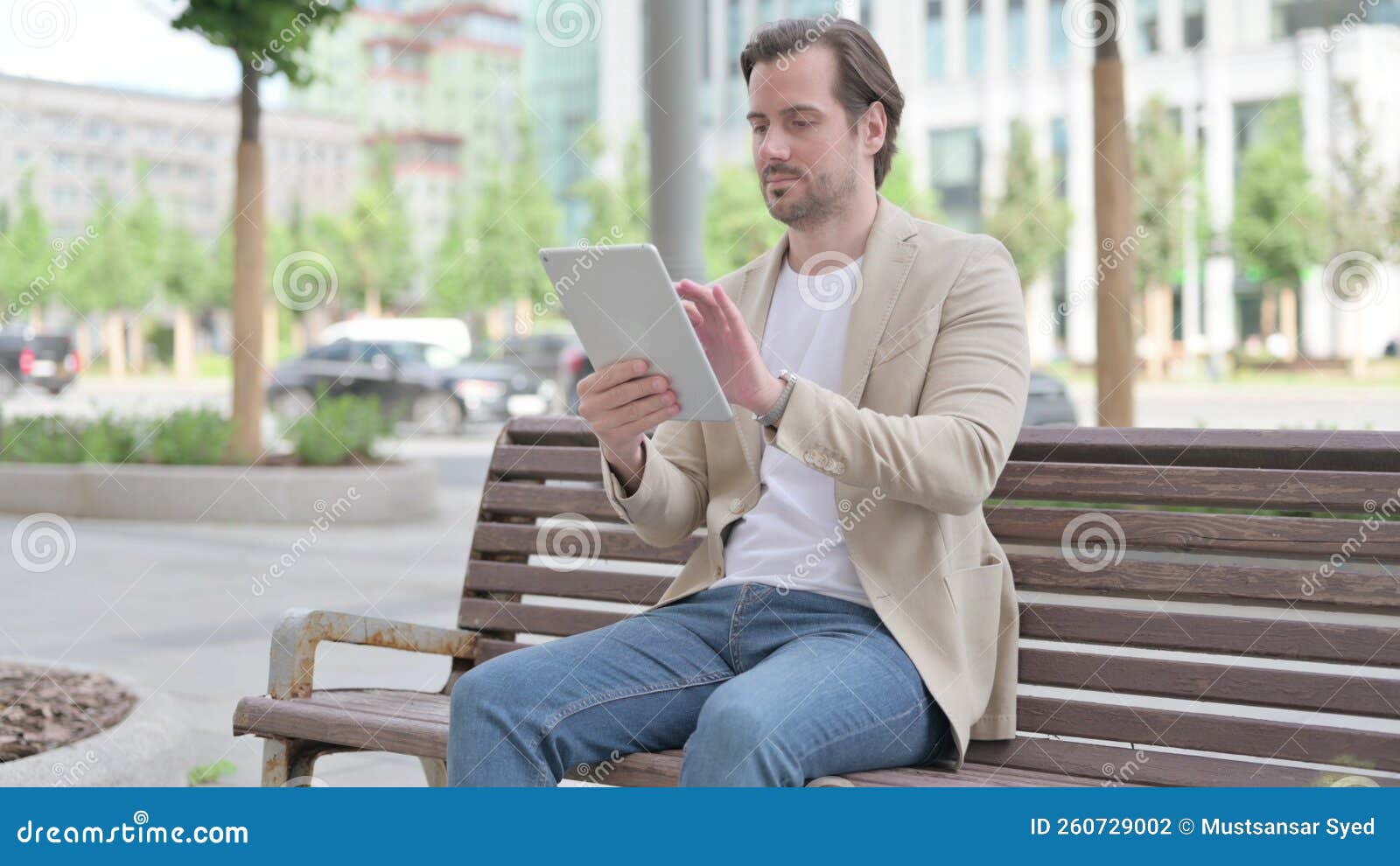 Young Man Using Tablet while Sitting on Bench Stock Photo - Image of ...