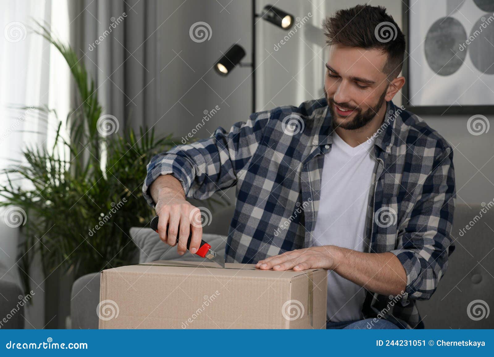 Man Using Utility Knife To Open Parcel at Home Stock Image - Image of ...