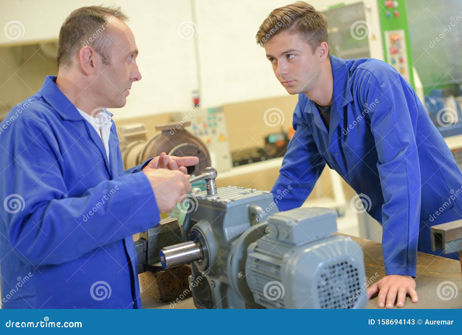 Man Using Wrench on Machine Apprentice Watching Stock Image - Image of ...