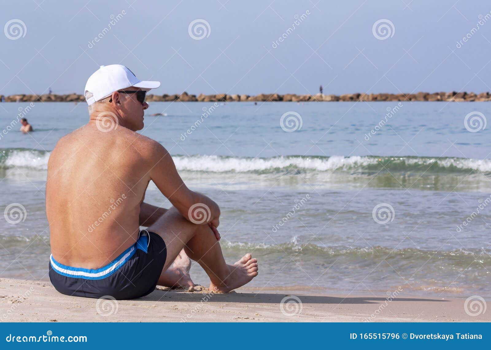 A Man in Swimming Trunks Sitting on the Beach Stock Photo - Image of ...