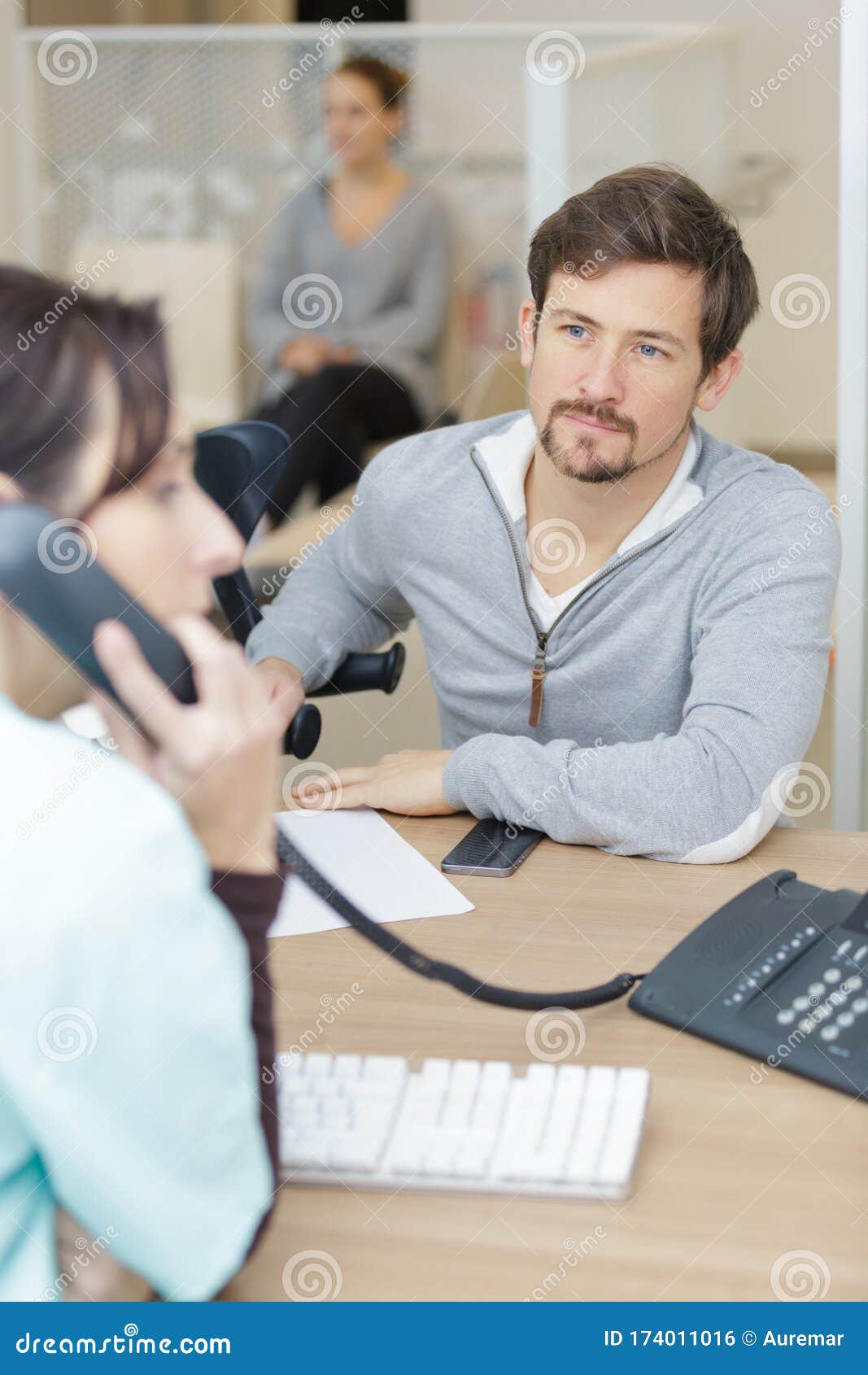 Man Waiting while Medical Receptionist Talks on Telephone Stock Photo ...