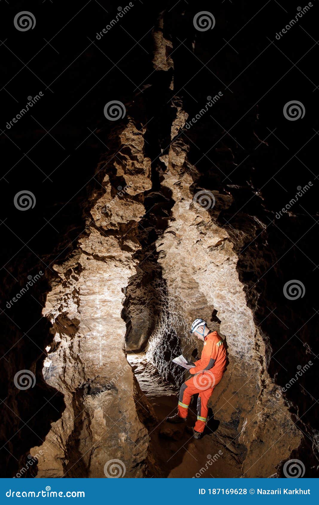 Man Walking and Exploring Dark Cave with Light Headlamp and Map in His ...