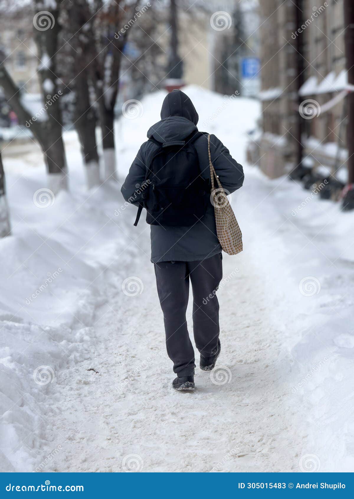 A Man Walks through the Snow in the City in Winter. Back View Stock ...