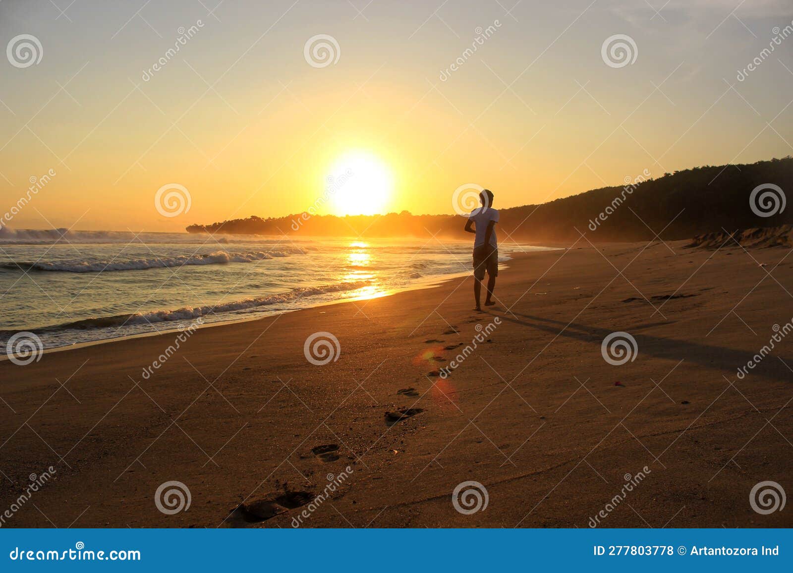 A Man Walks into the Sunset, Leaving Footprints in the Sand. Far View ...